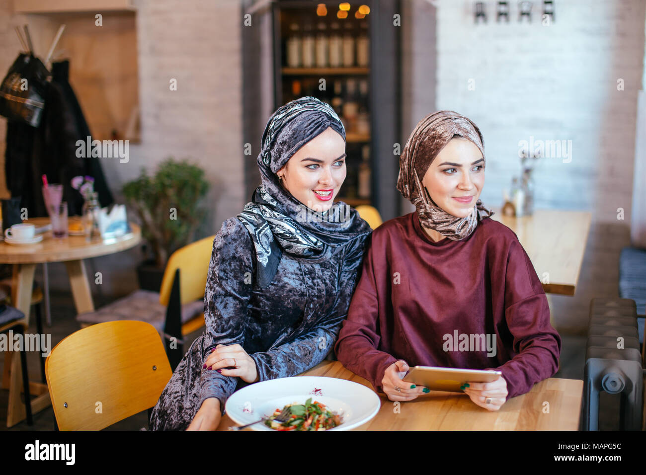 Two Muslim women in cafe, shop online using electronic tablet Stock ...