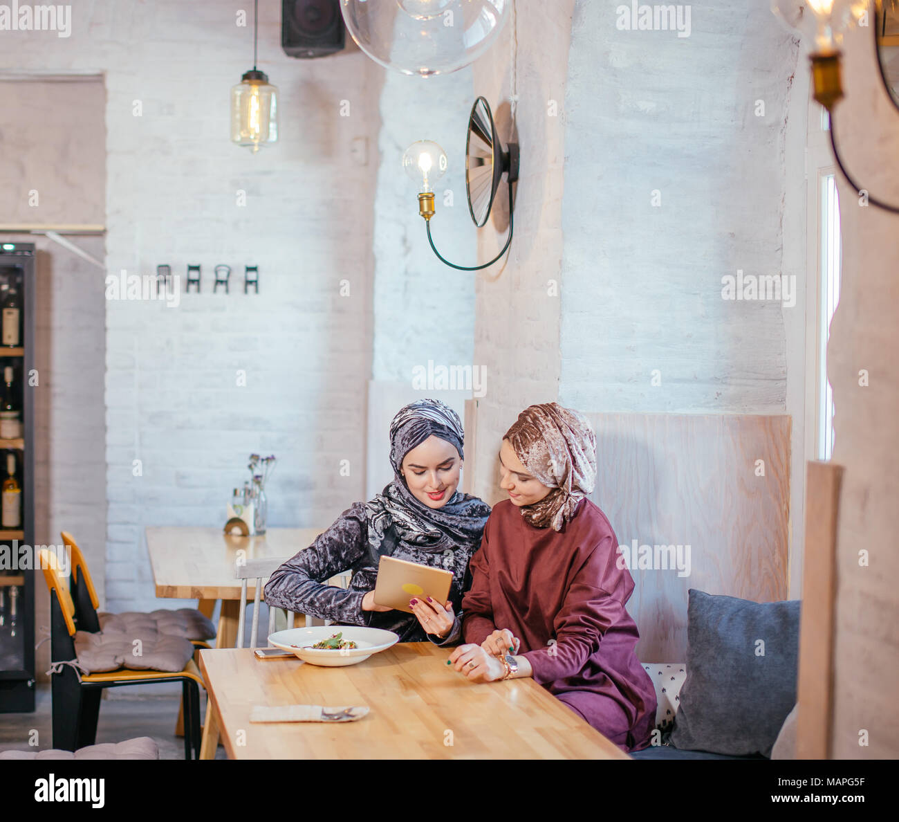 Two Muslim women in cafe, shop online using electronic tablet Stock ...