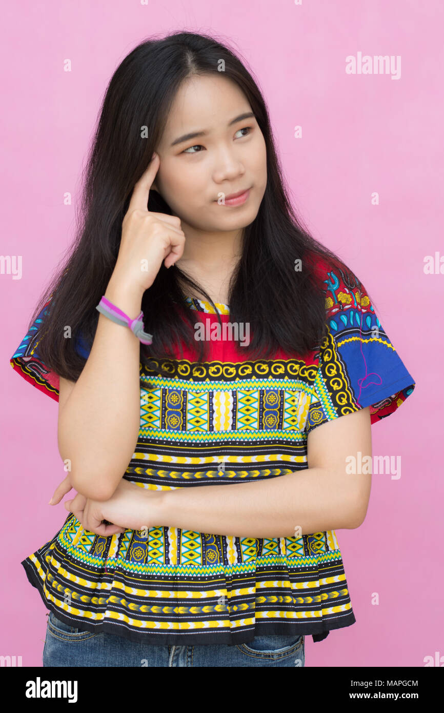 Portrait of a beautiful young girl thinks something isolated on pink ...