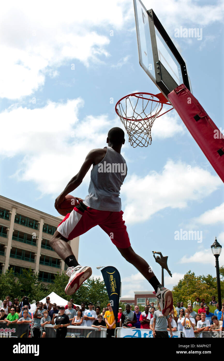 A young man jumps high attempting a reverse dunk in the slam dunk ...