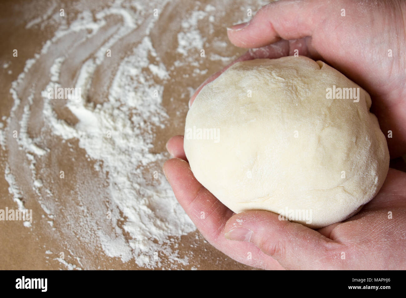 The dough in his hands on the table with flour Stock Photo - Alamy