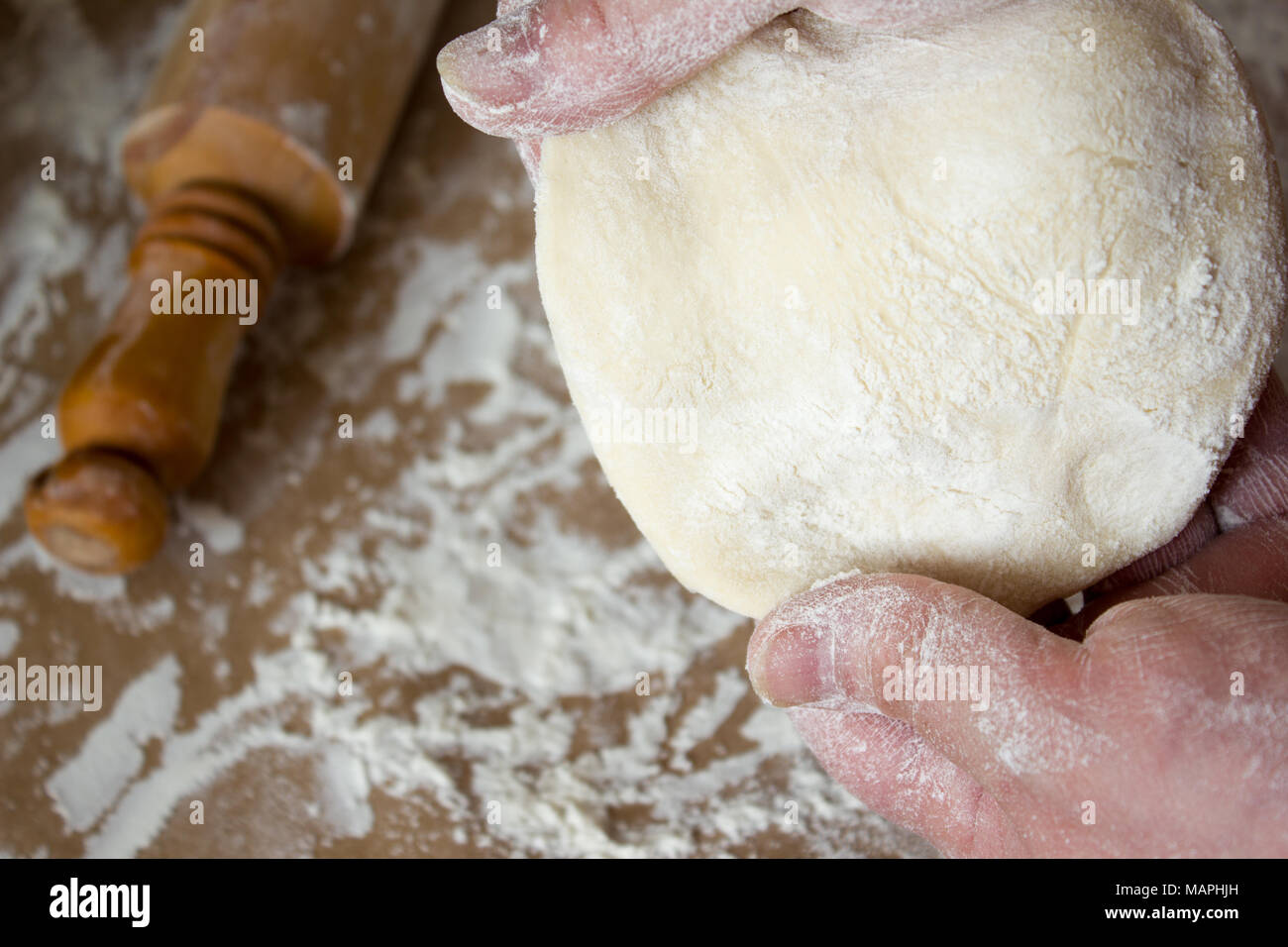 The dough in his hands on the table with flour Stock Photo - Alamy