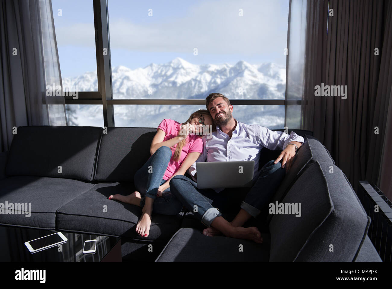 Young couple relaxing at home using laptop computers reading in the ...