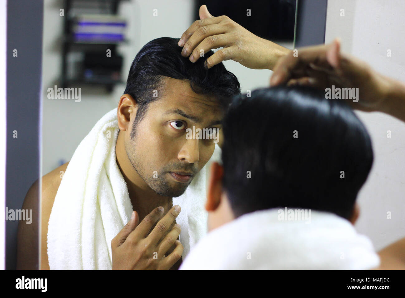 indian asian man looking after his appearance in front of a mirror ...