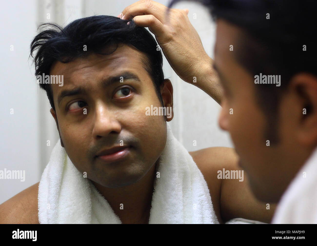 indian asian man looking after his appearance in front of a mirror ...