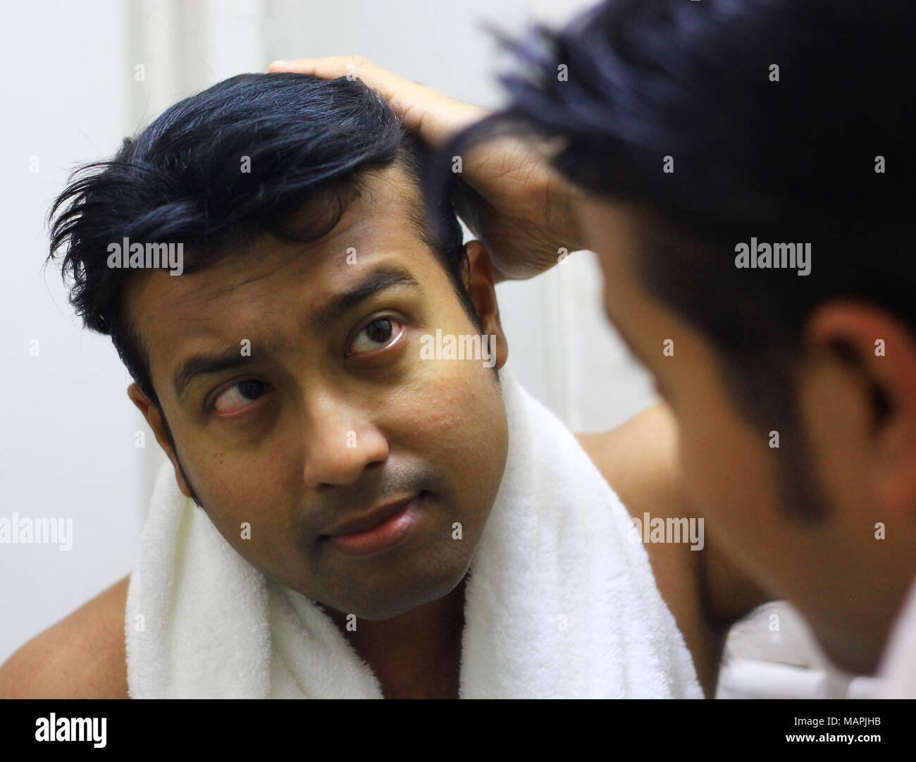 indian asian man looking after his appearance in front of a mirror ...