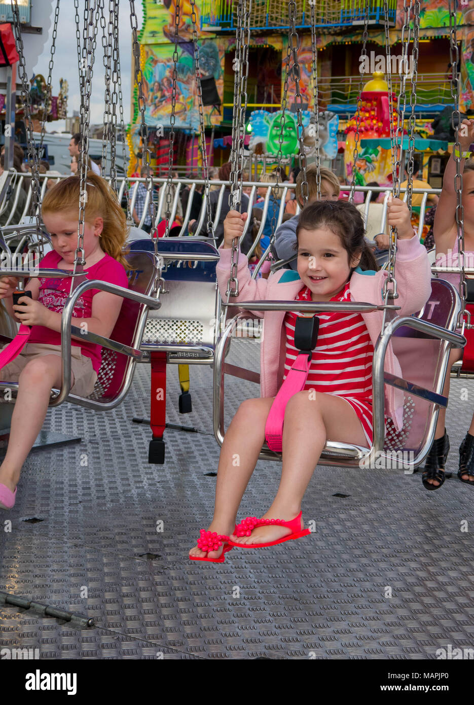 Two young girls on a swing carousel at a fairground Stock Photo - Alamy