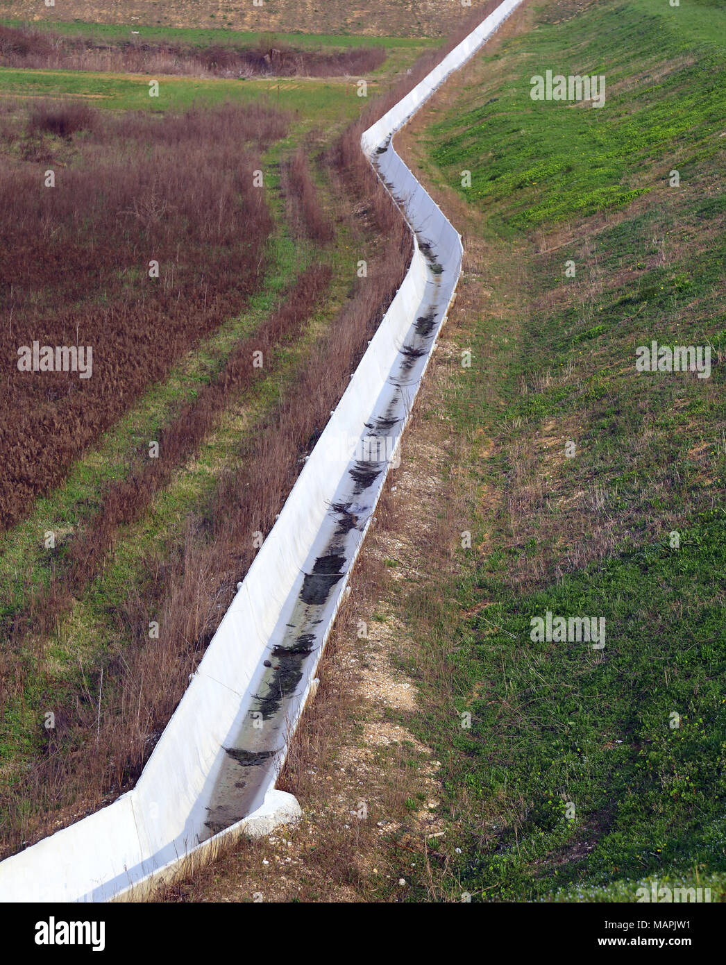 white concrete ditch on the field to transport water for irrigation ...