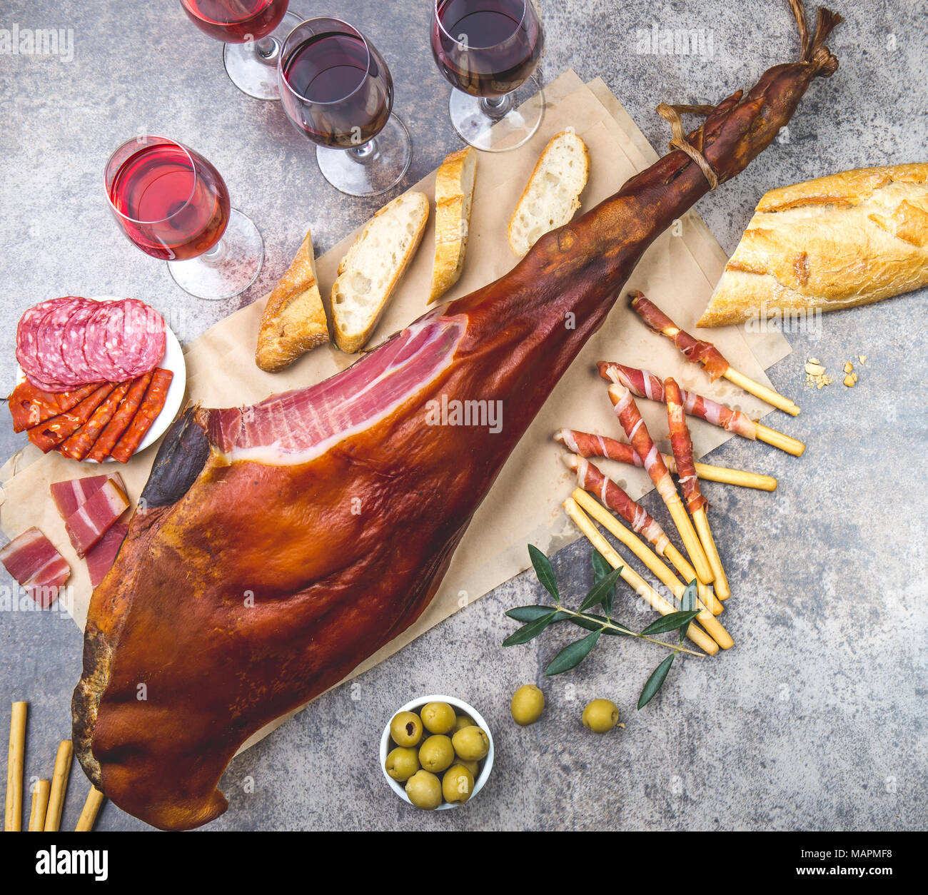 Whole leg HAM JAMON SERRANO and red and rose wine on gray background ...