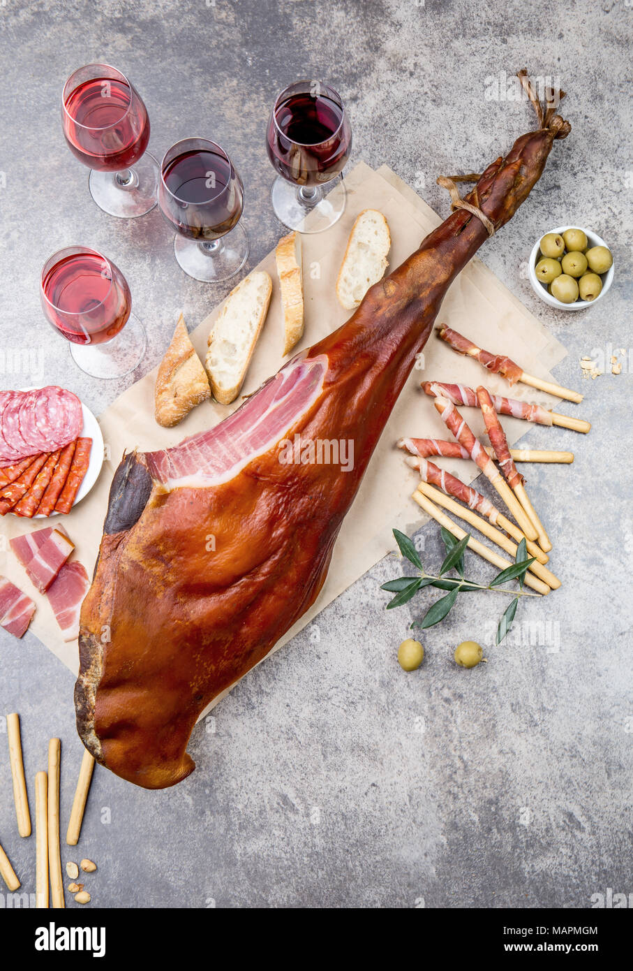 Whole leg HAM JAMON SERRANO and red and rose wine on gray background ...