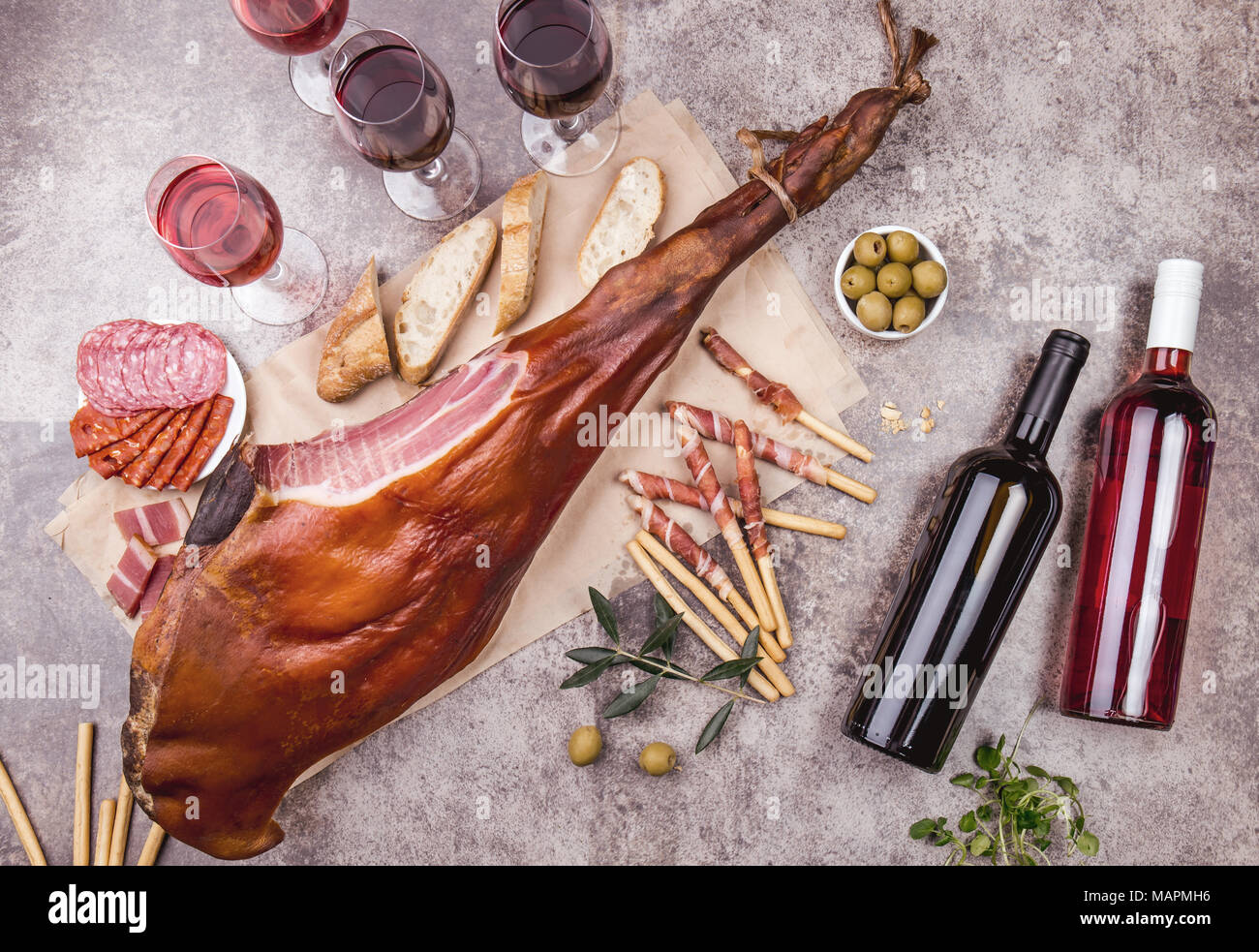 Whole leg HAM JAMON SERRANO and red and rose wine on gray background ...