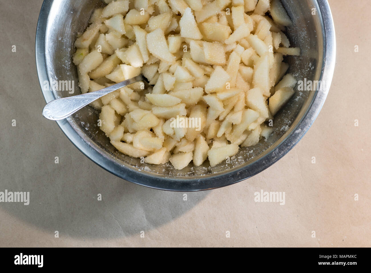 Chopped peeled pears mixed with sugar and a spoon in a metal bowl Stock ...