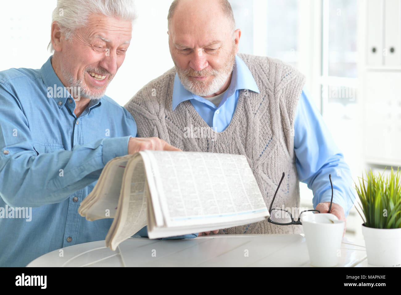 Two senior men reading newspaper Stock Photo - Alamy