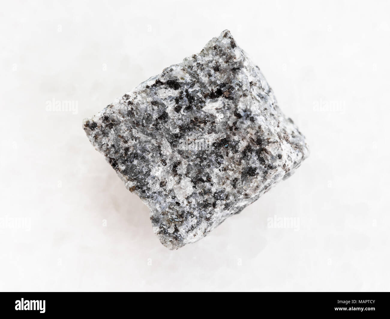 macro shooting of natural mineral rock specimen - raw Gabbro stone on white marble background ...