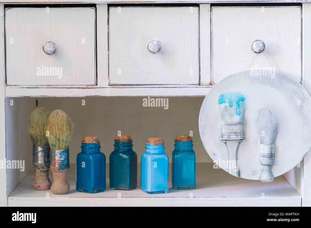 Colorful bottles with paints, brushes and a handmade ceramic plate on ...
