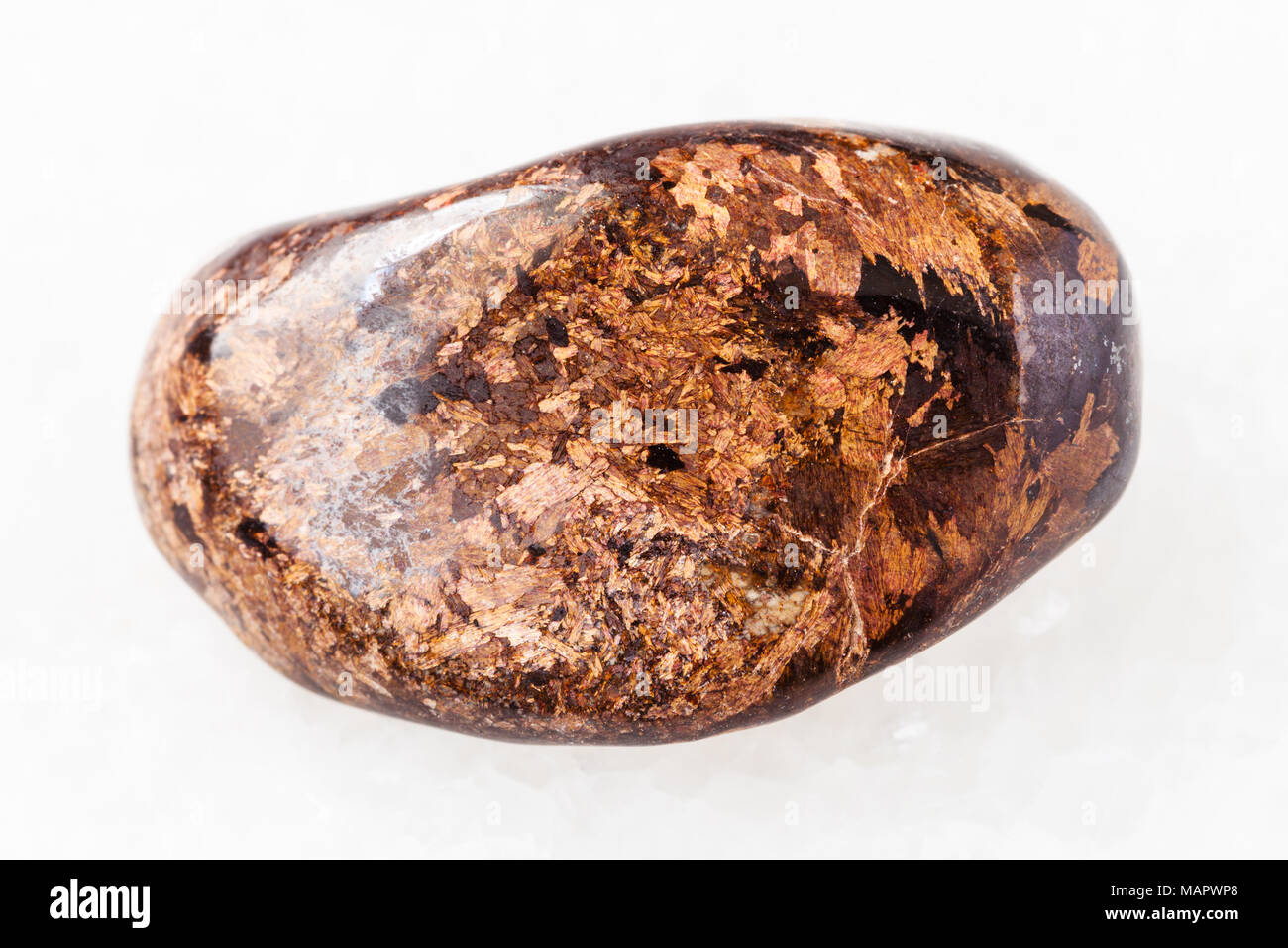 macro shooting of natural mineral rock specimen - polished Bronzite gemstone on white marble ...