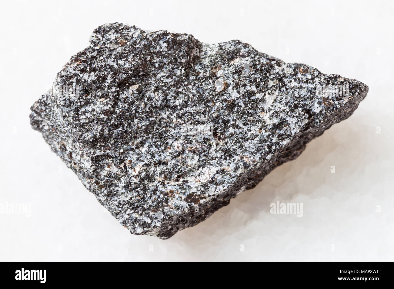 macro shooting of natural mineral rock specimen - raw nepheline syenite stone on white marble ...