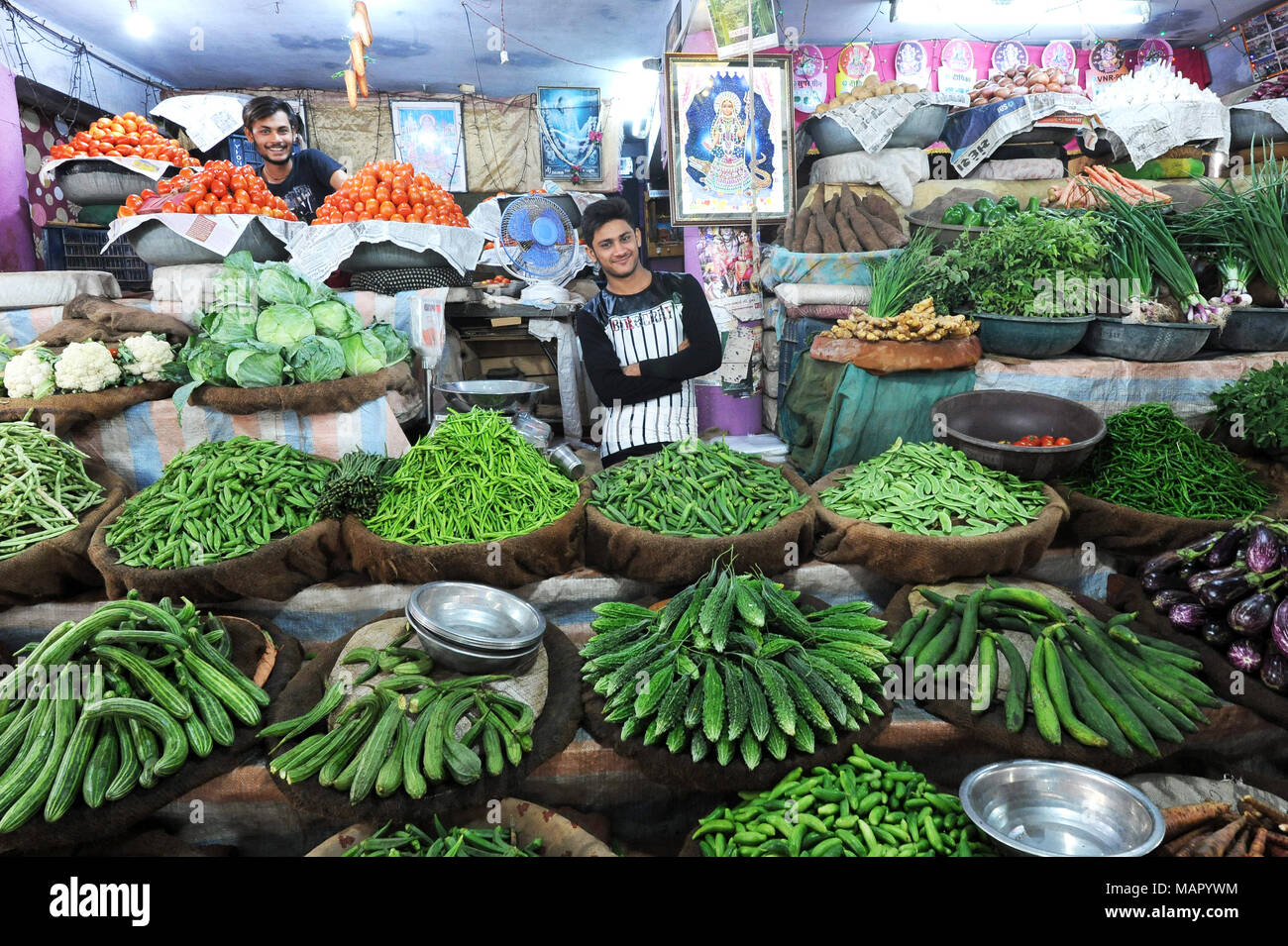 Two cheerful young men running a fresh vegetable stall in the main city ...