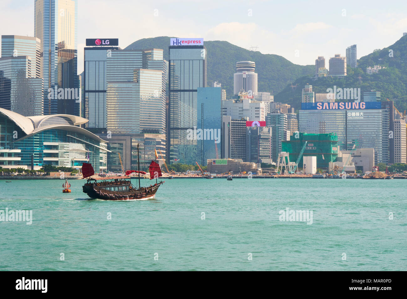 Traditional junk boat on Victoria Harbour with city skyline behind ...