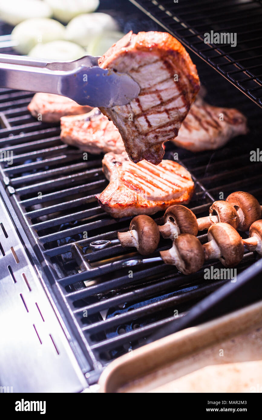 Grilling pork chops on gas grill in the Summer Stock Photo - Alamy