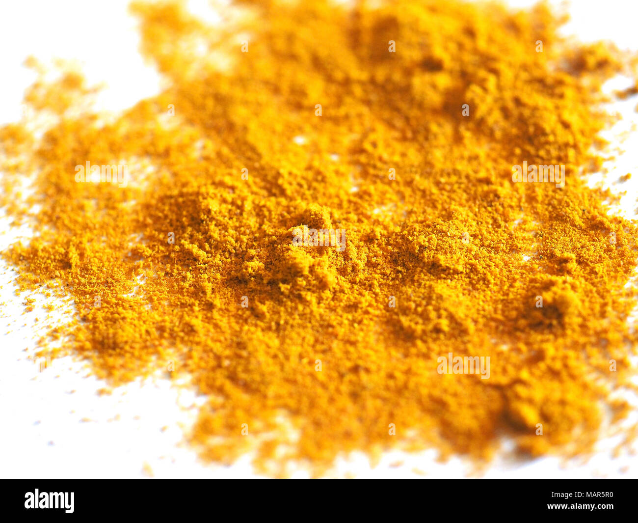 Curry powder is a blend of hot Indian spices over white background ...