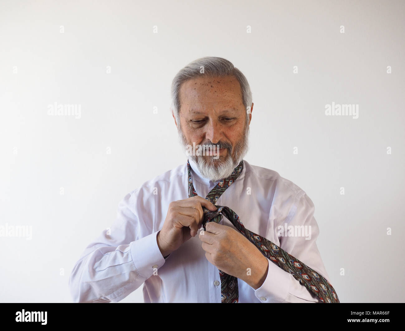Elegant smart dressed man tying a tie with Half Windsor knot Stock ...