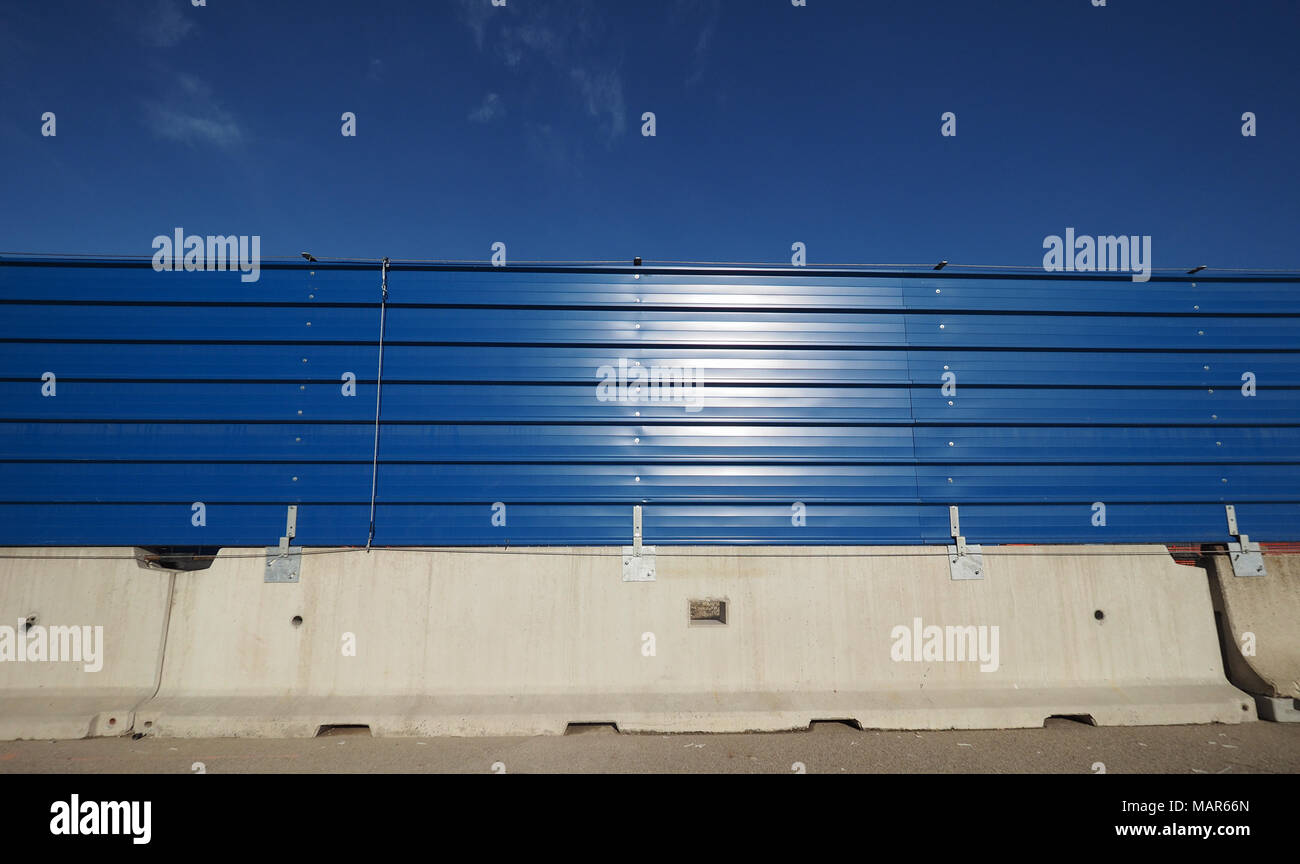 concrete barrier with blue metal fence over blue sky with copy space ...