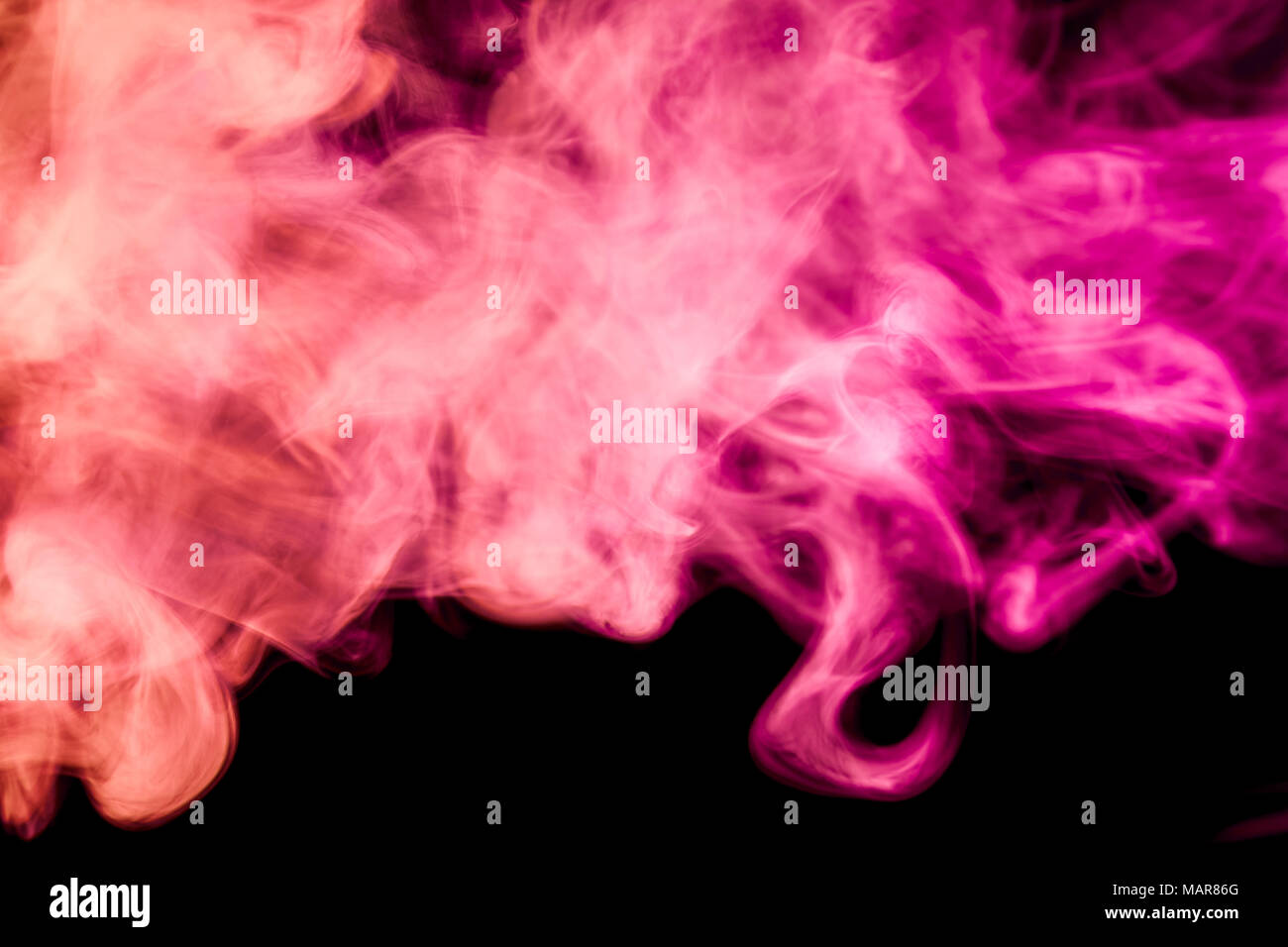 Dense pink and red multicolored smoke on a black isolated background ...