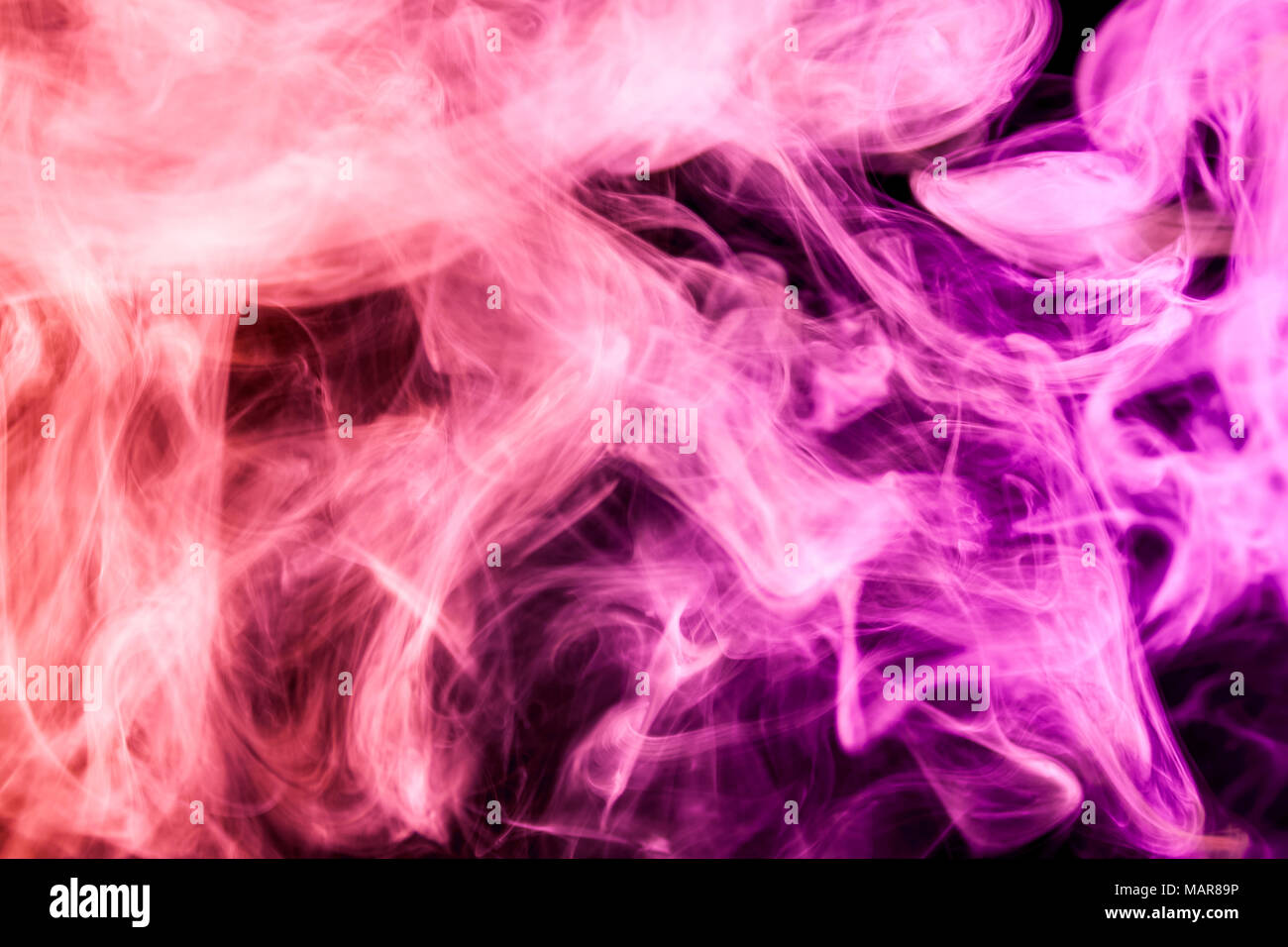 Dense pink and red multicolored smoke on a black isolated background ...