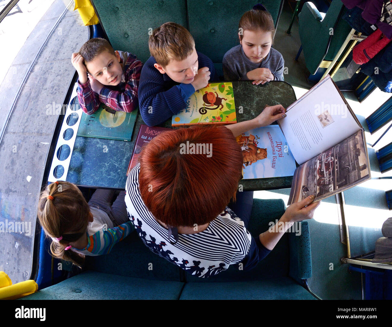 Reading club in streetcar cabin: teacher showing children pictures in ...