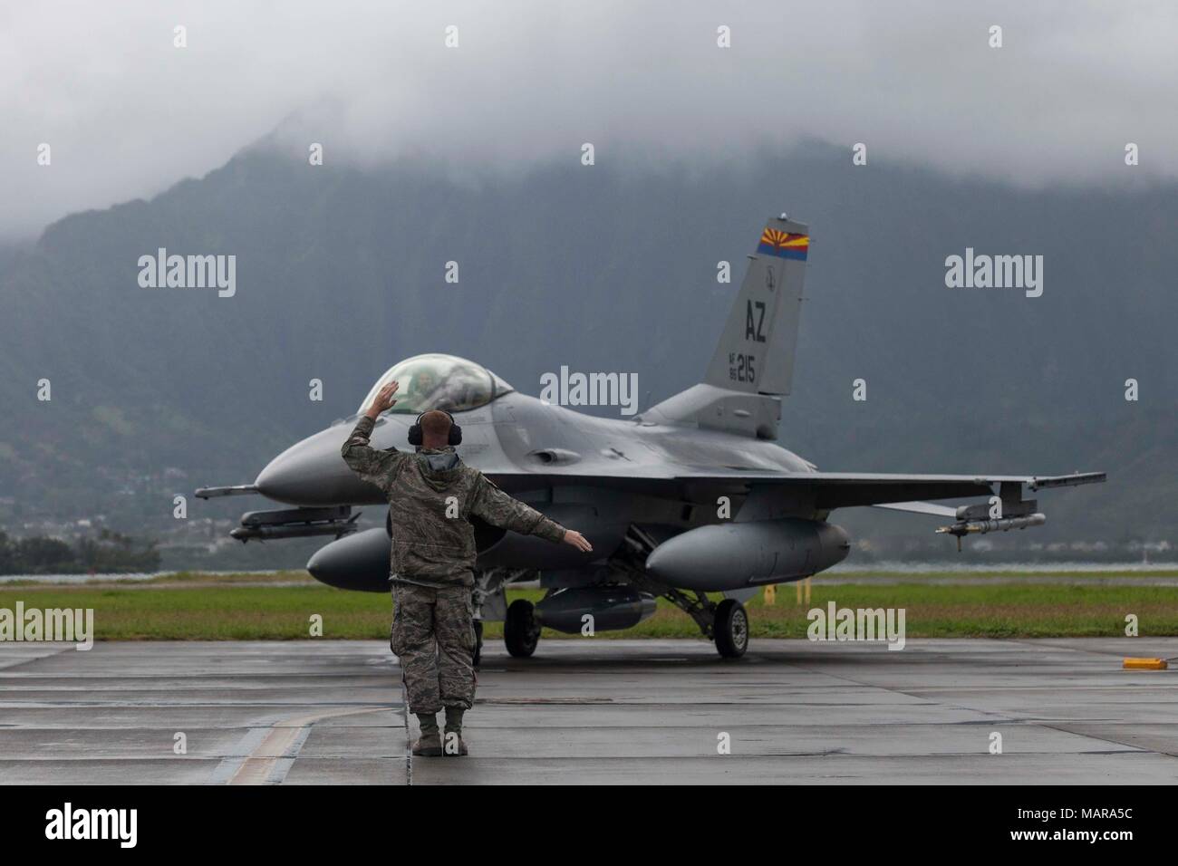 A U.S. Airman guides an F-16 Fighting Falcon fighter jet assigned to ...
