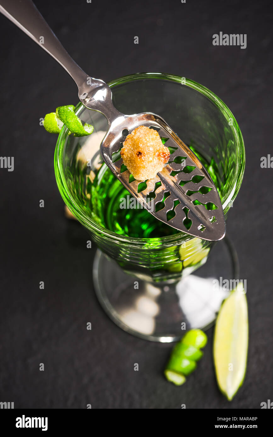 Carmelized sugar cube over green Absinthe vodka Stock Photo - Alamy