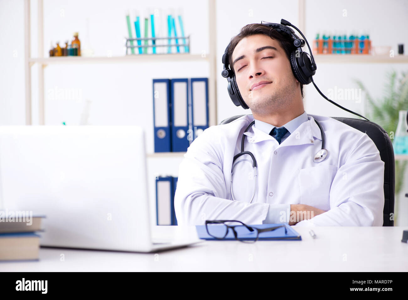 Happy excited doctor listening to music during lunch break in hospital ...