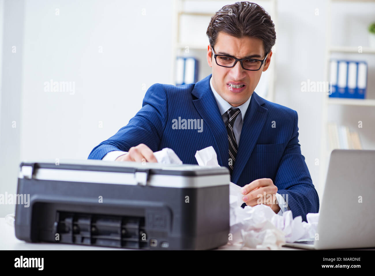 Businessman angry at copying machine jamming papers Stock Photo - Alamy