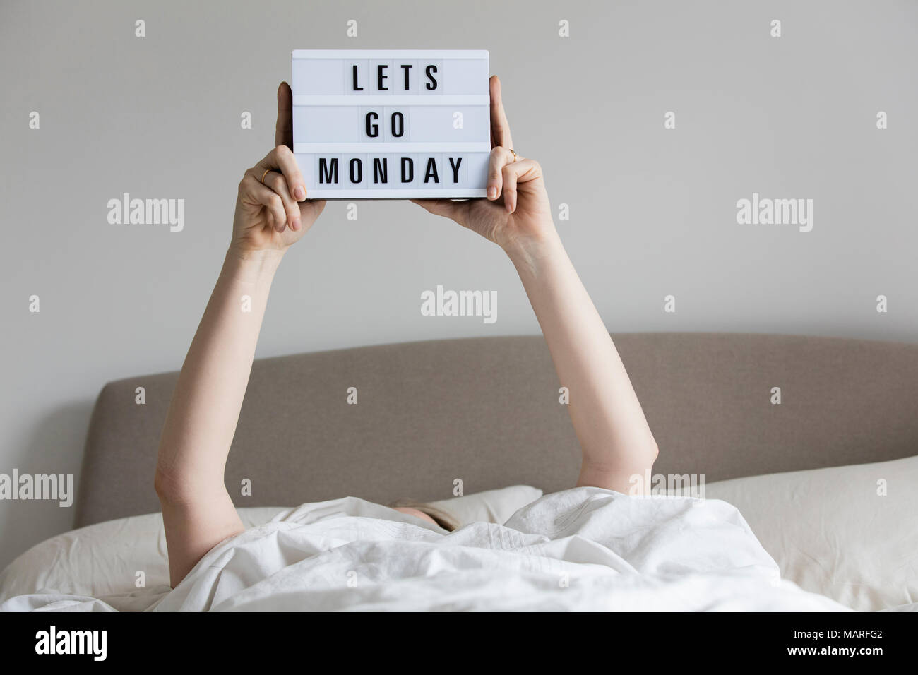 Female in bed under the sheets holding up a lets go monday sign Stock ...