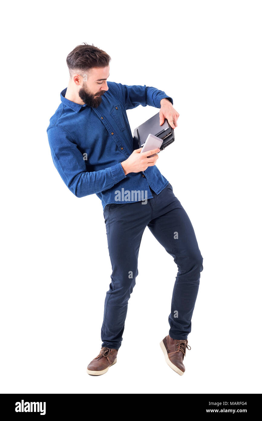 Clumsy young bearded businessman holding laptop, tablet and cell phone ...