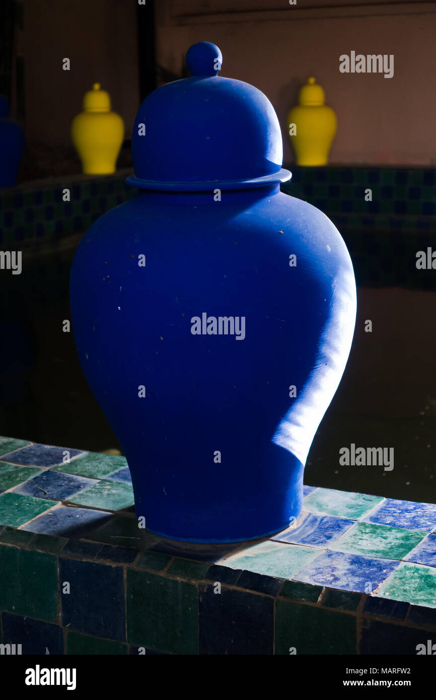 Blue and yellow pots at the edge of tiled fish pond in Majorelle garden ...