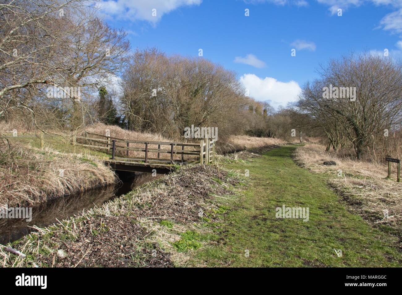 winterA early spring view along a drainage ditch with a wooden bridge ...