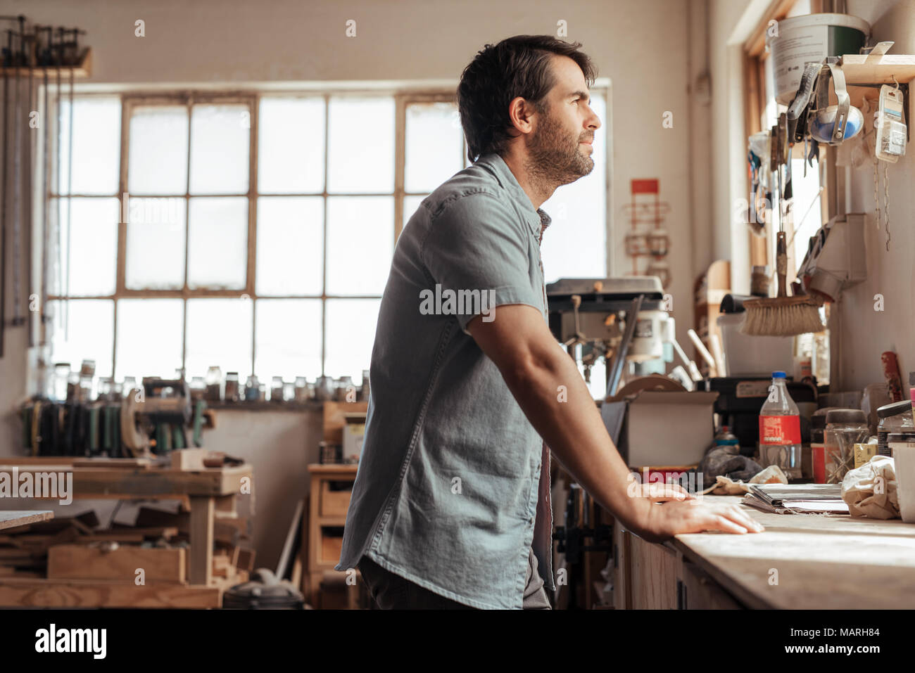 Skilled young woodworker leaning on a workbench deep in thought Stock ...