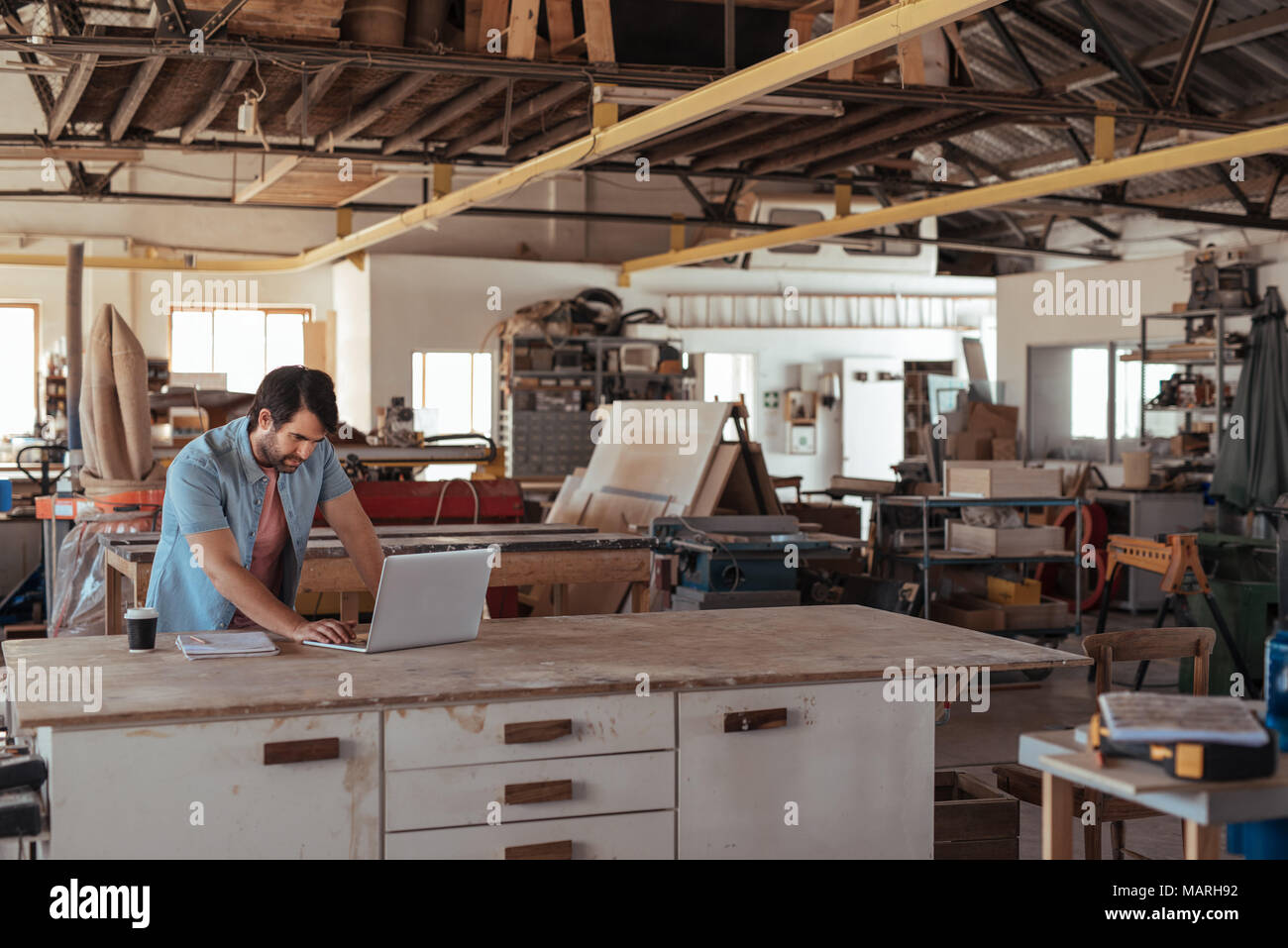 Young woodworker working online at a bench in his workshop Stock Photo ...