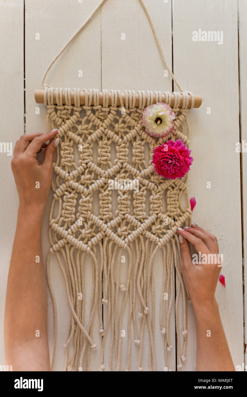 Artist hands holding macrame wall art with some spring flowers on it ...