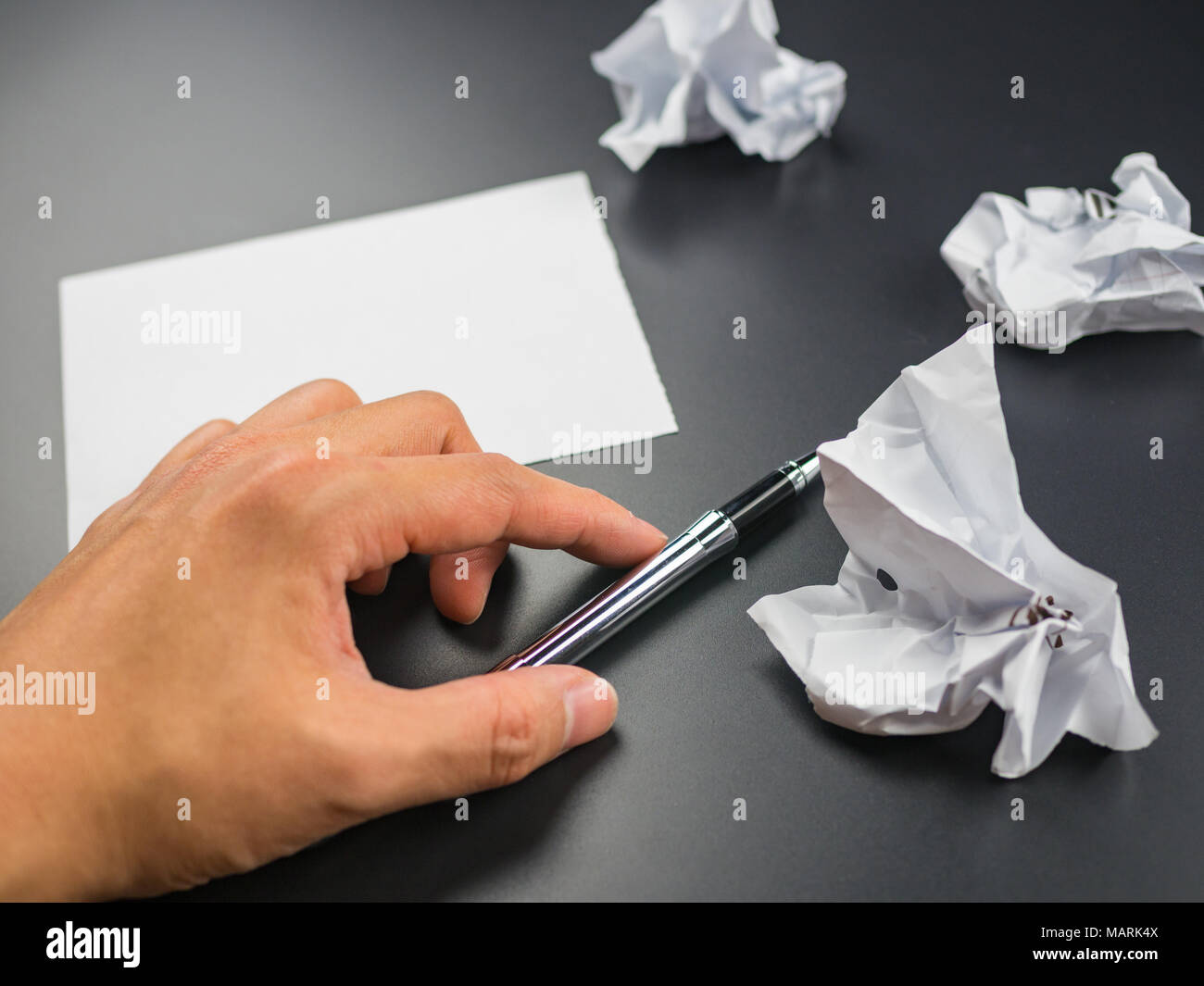 Hand with pen and crumpled paper balls on black background Stock Photo ...
