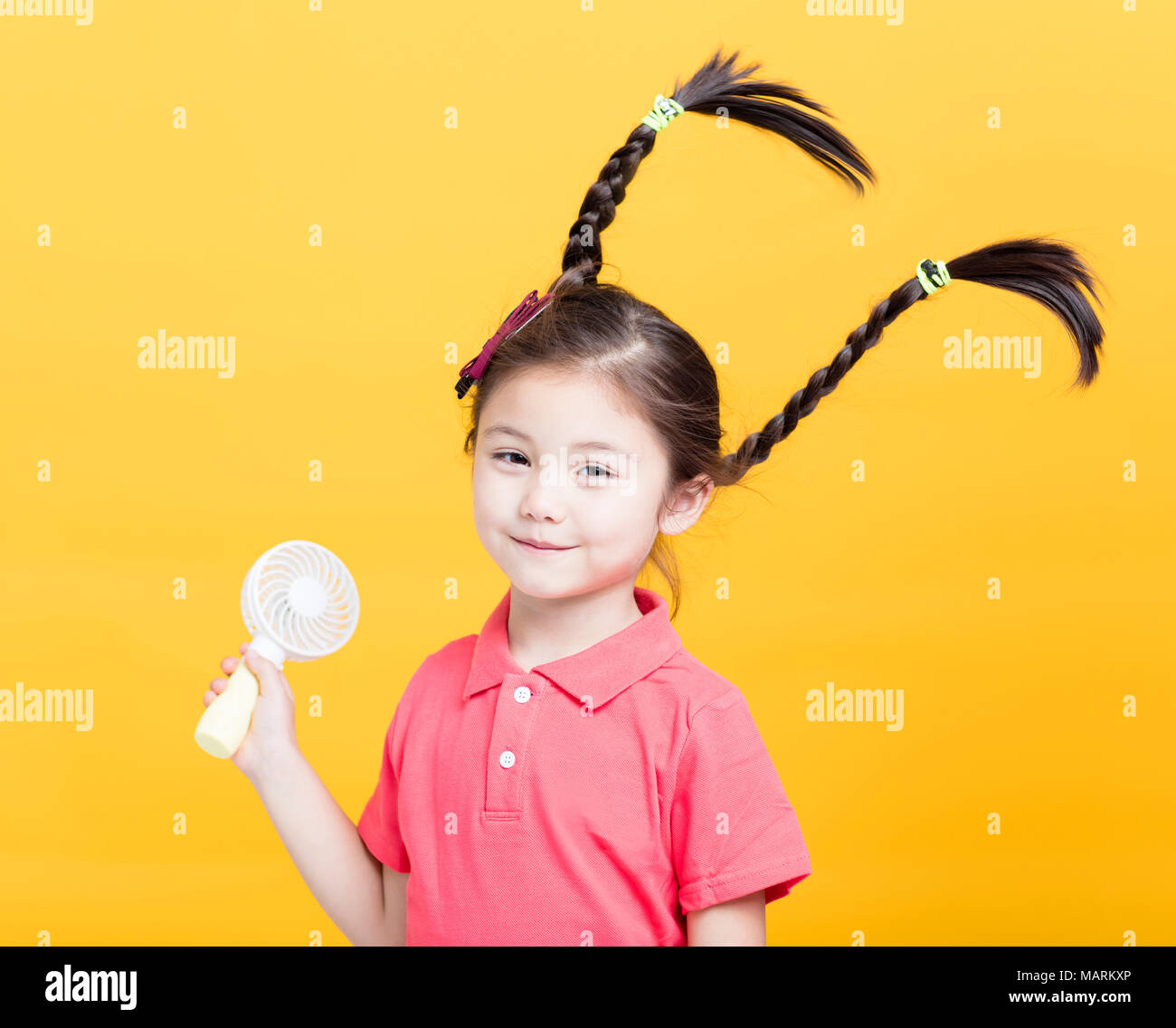 smiling little girl enjoying cool wind from electric fan Stock Photo ...