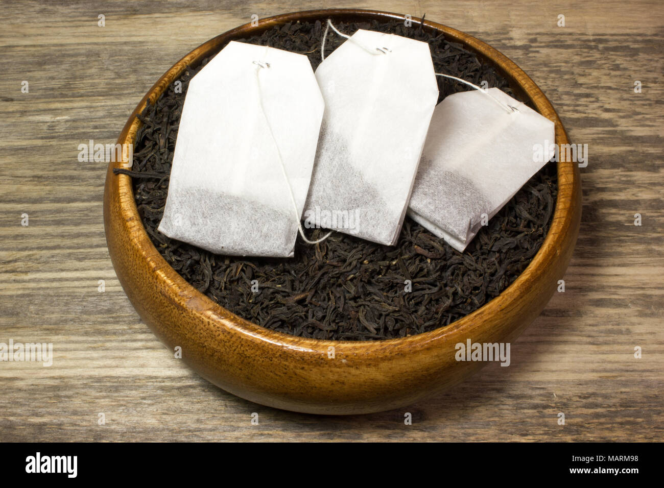 Dry tea leaves for black tea and paper tea bag on wooden background ...
