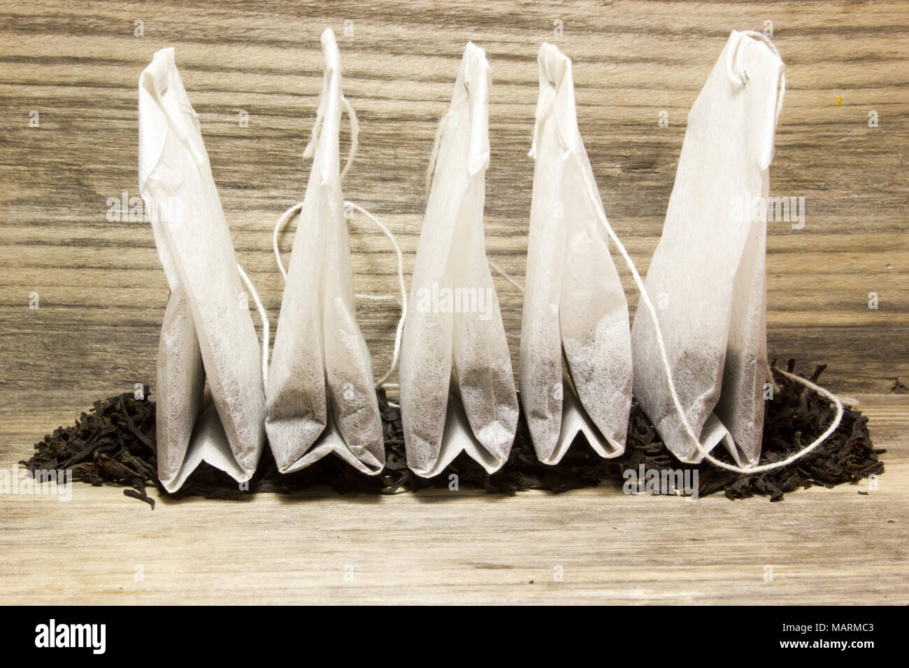 Dry tea leaves for black tea and paper tea bag on wooden background ...