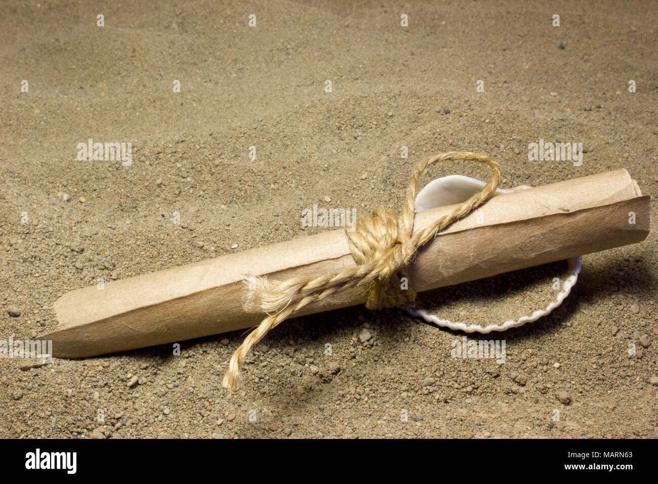 A roll of paper on the sand. Message for help Stock Photo - Alamy
