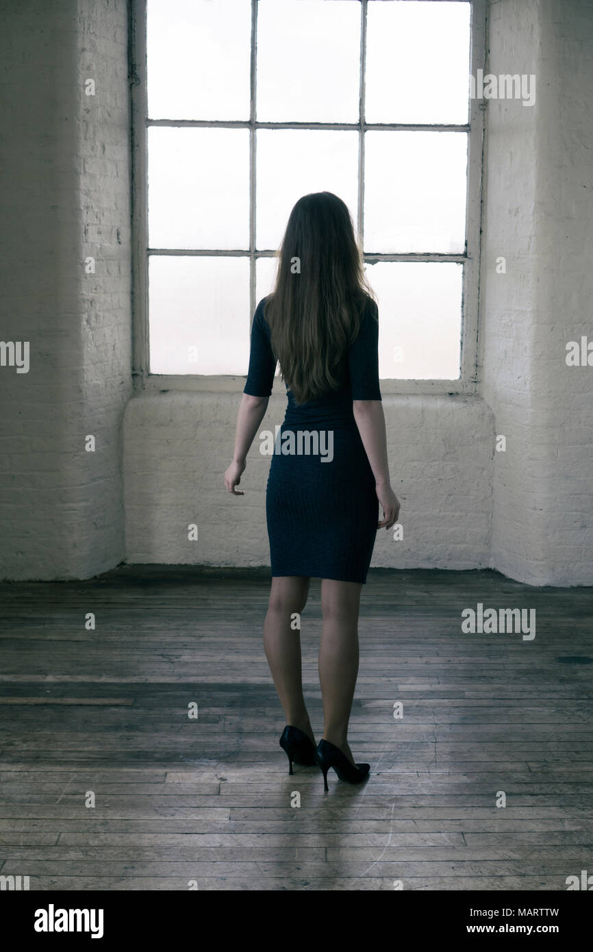 Rear view of a woman standing by the window Stock Photo - Alamy