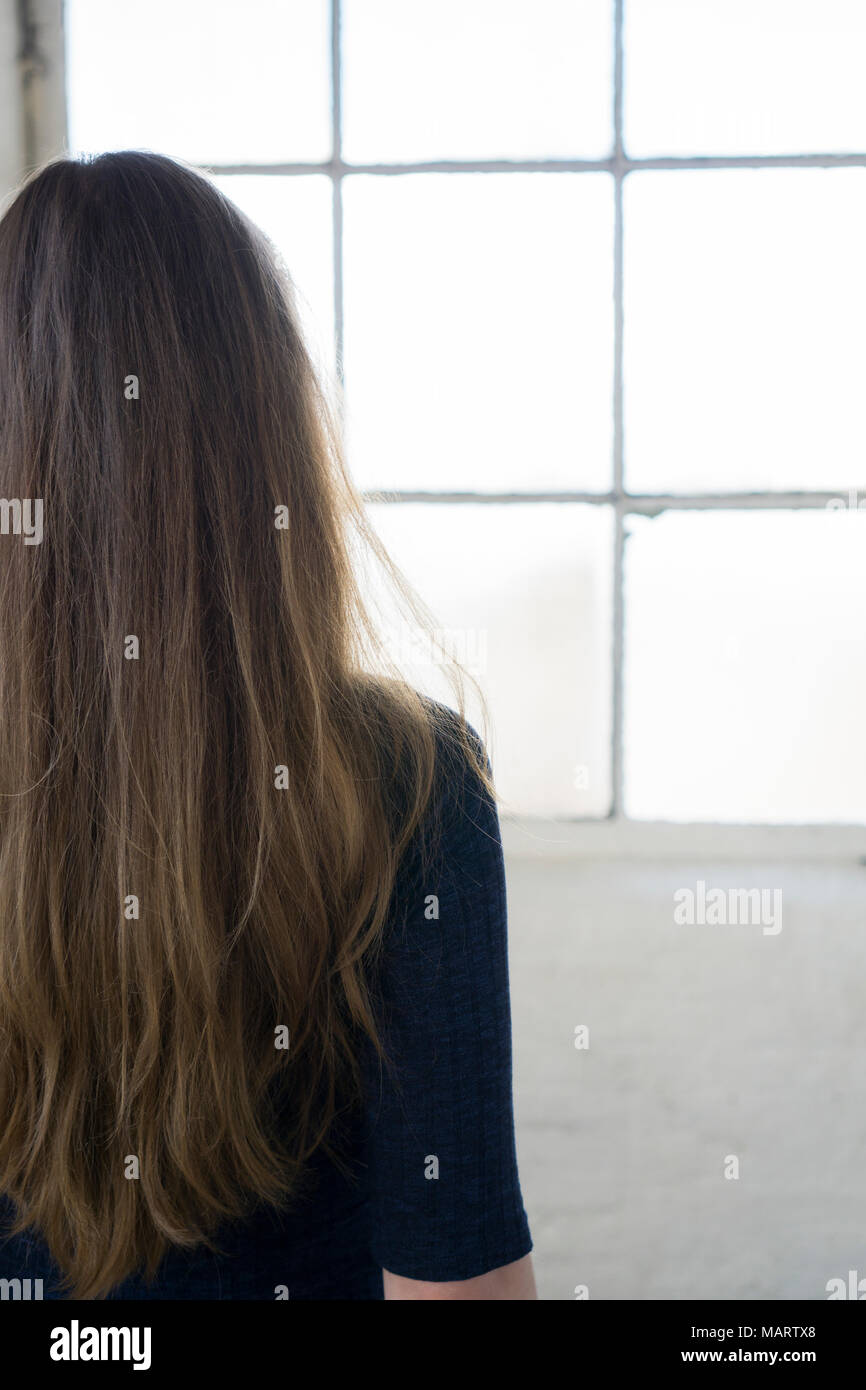 Rear view of a woman standing by the window Stock Photo - Alamy
