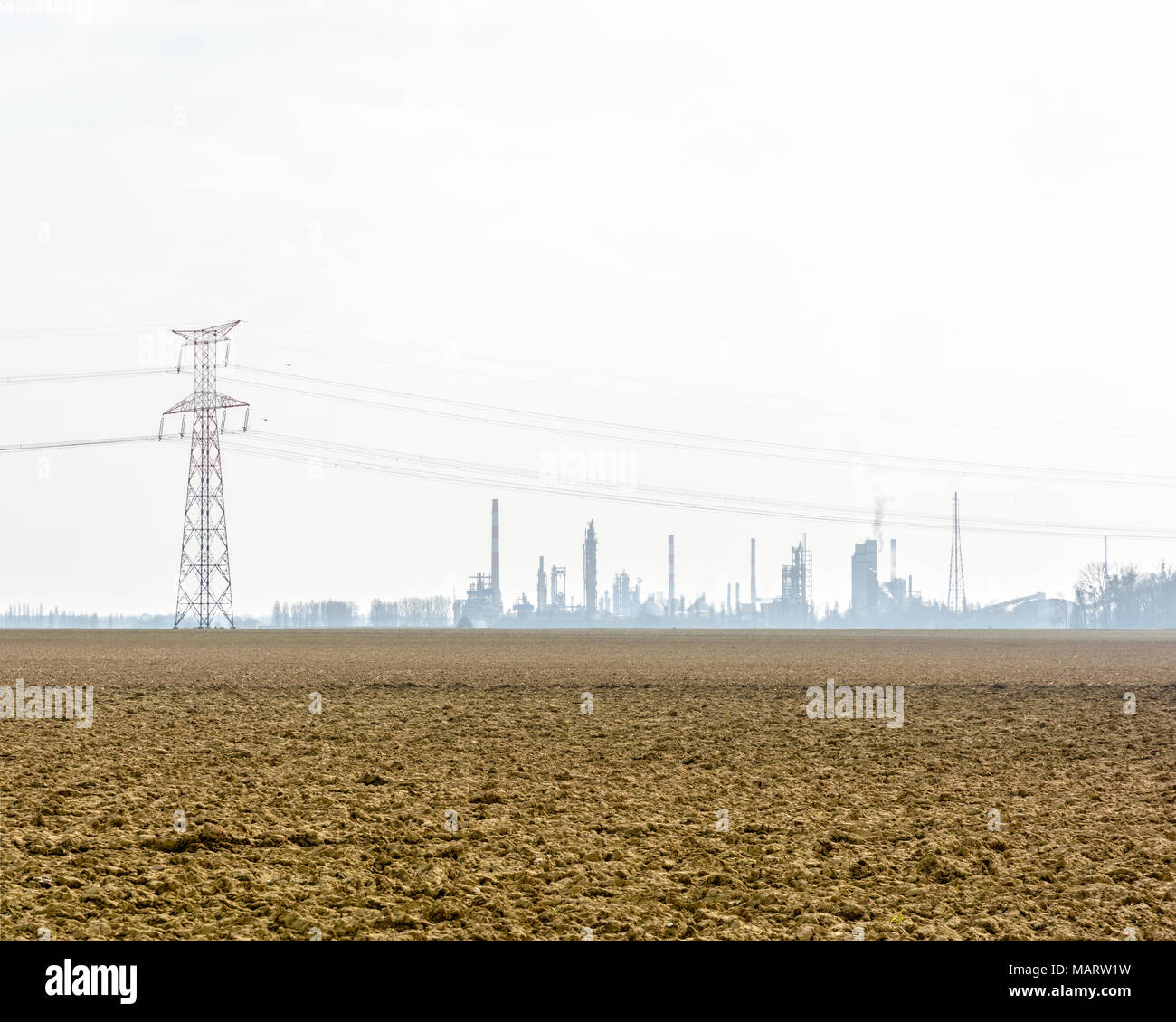 A plowed land with a transmission tower, a high-voltage power line and ...