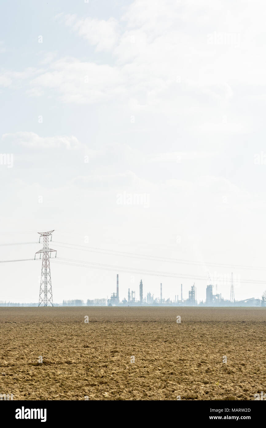A plowed land with a transmission tower, a high-voltage power line and ...